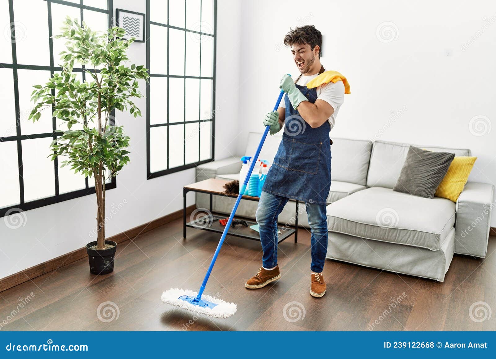 Young Hispanic Man Doing Chores Singing Using Mop As a Microphone at ...