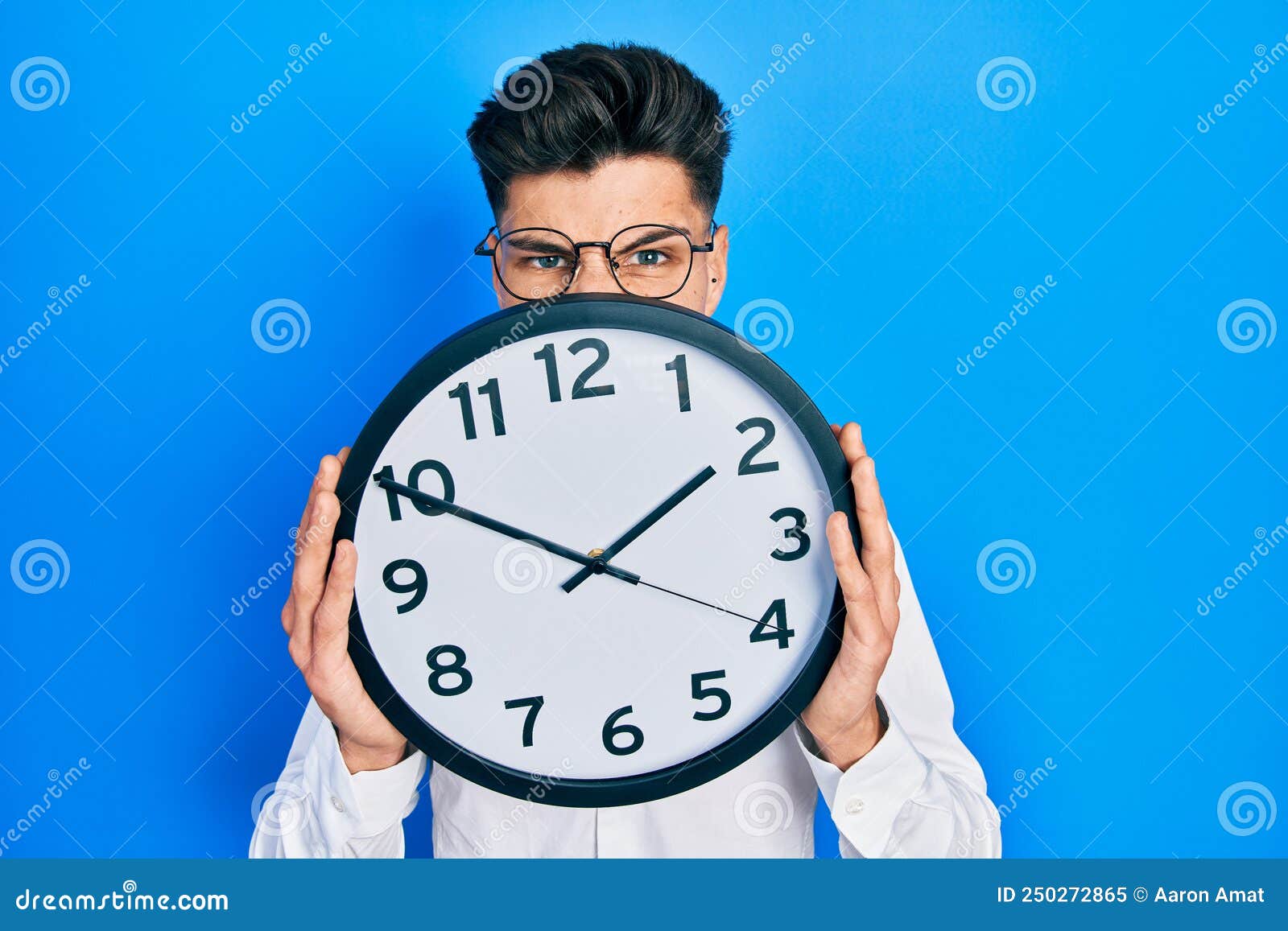 Young Hispanic Man Holding Big Clock Over Face Clueless and Confused ...