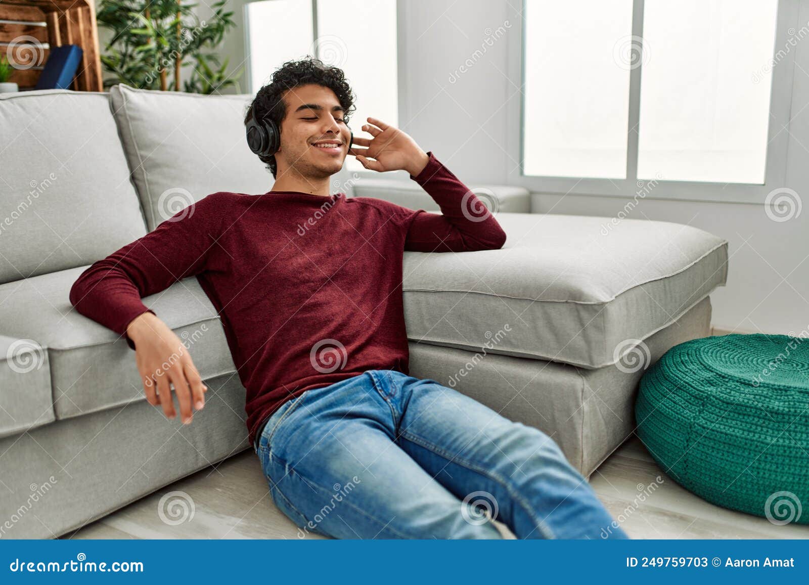 Young Hispanic Man Listening To Music Sitting On The Floor At Home