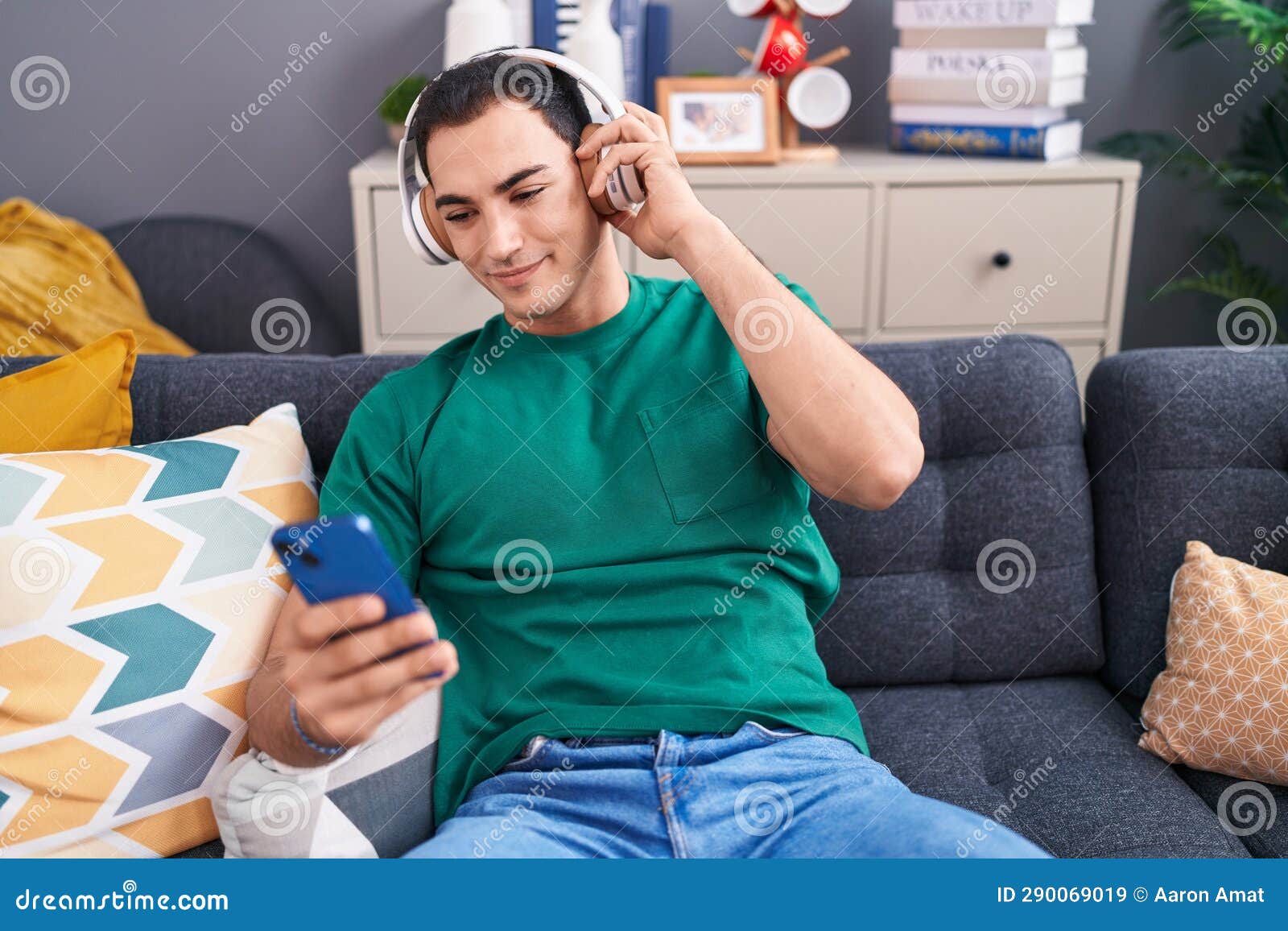 Young Hispanic Man Listening To Music Sitting On Sofa At Home Stock