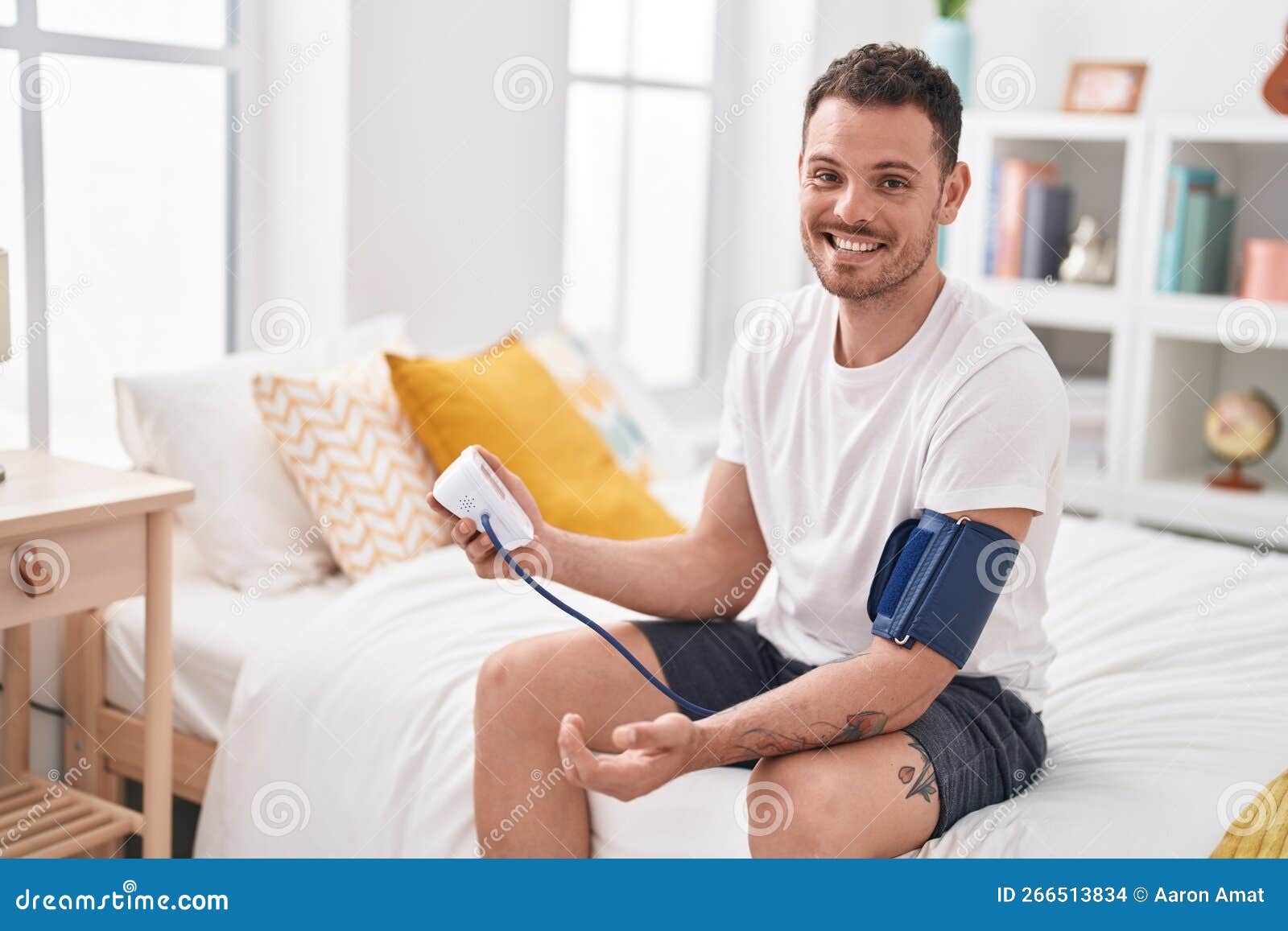 Young Hispanic Man Measuring Pulse Using Tensiometer at Bedroom Stock ...