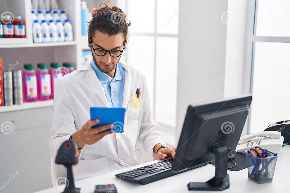 Young Hispanic Man Pharmacist Using Touchpad and Computer, Working at ...