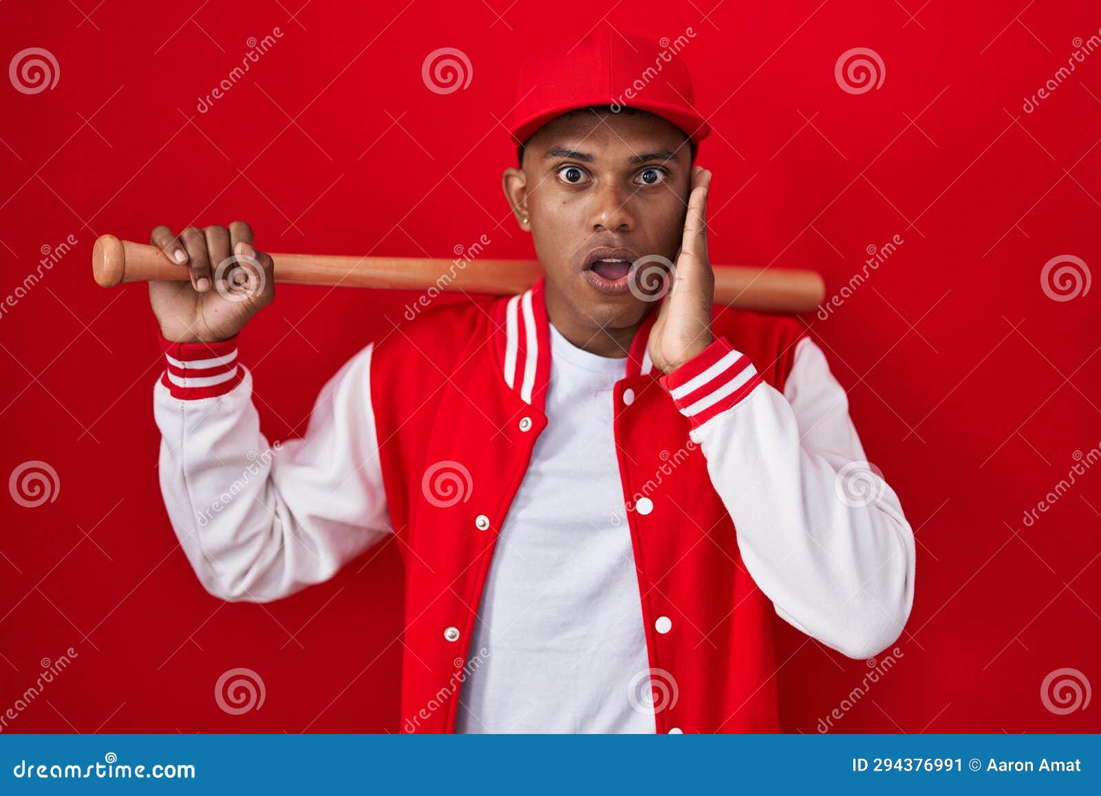 Young Hispanic Man Playing Baseball Holding Bat Afraid and Shocked ...