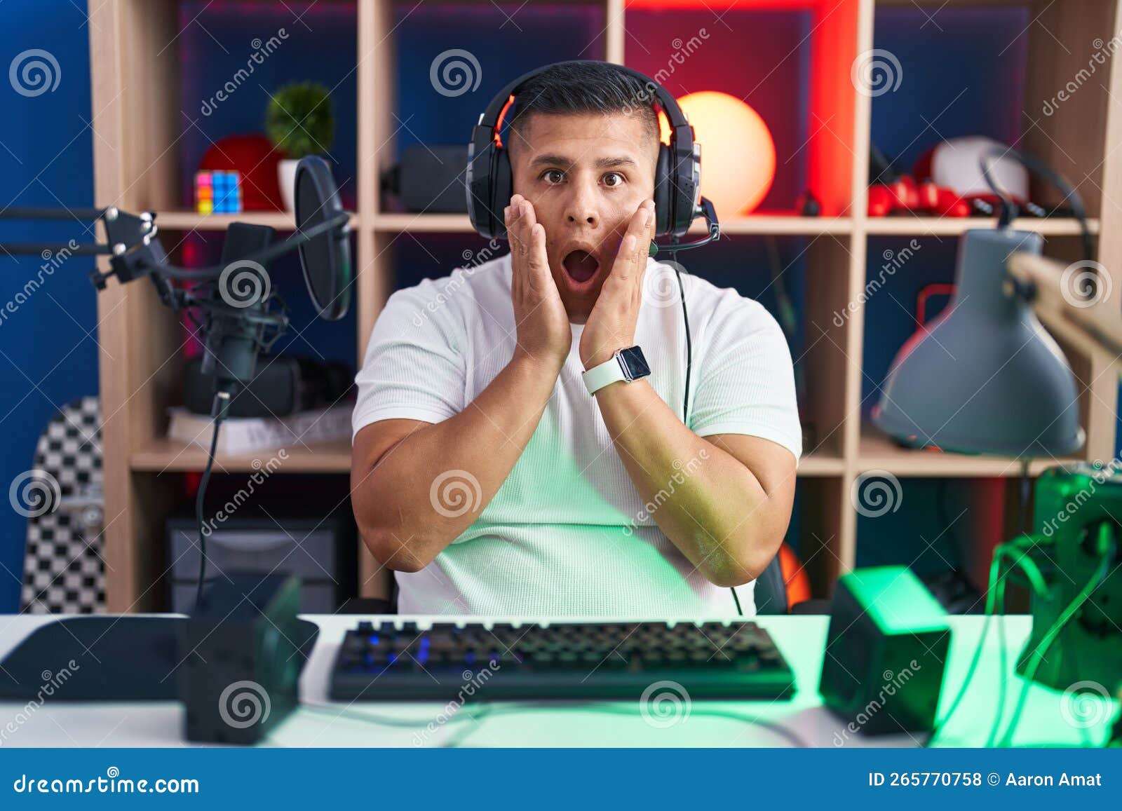 Young Hispanic Man Playing Video Games Afraid and Shocked, Surprise and ...