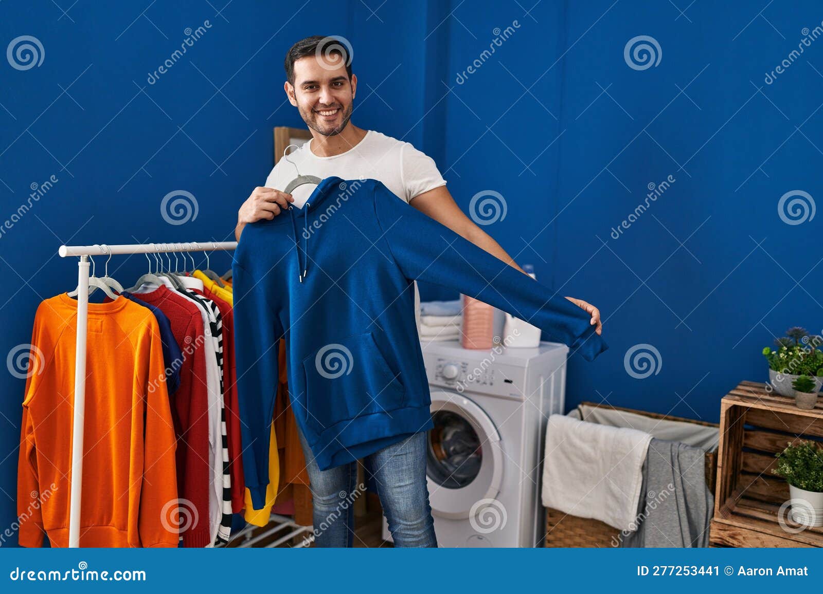 Young Hispanic Man Putting Clothes on Clothes Rack at Laundry Room ...