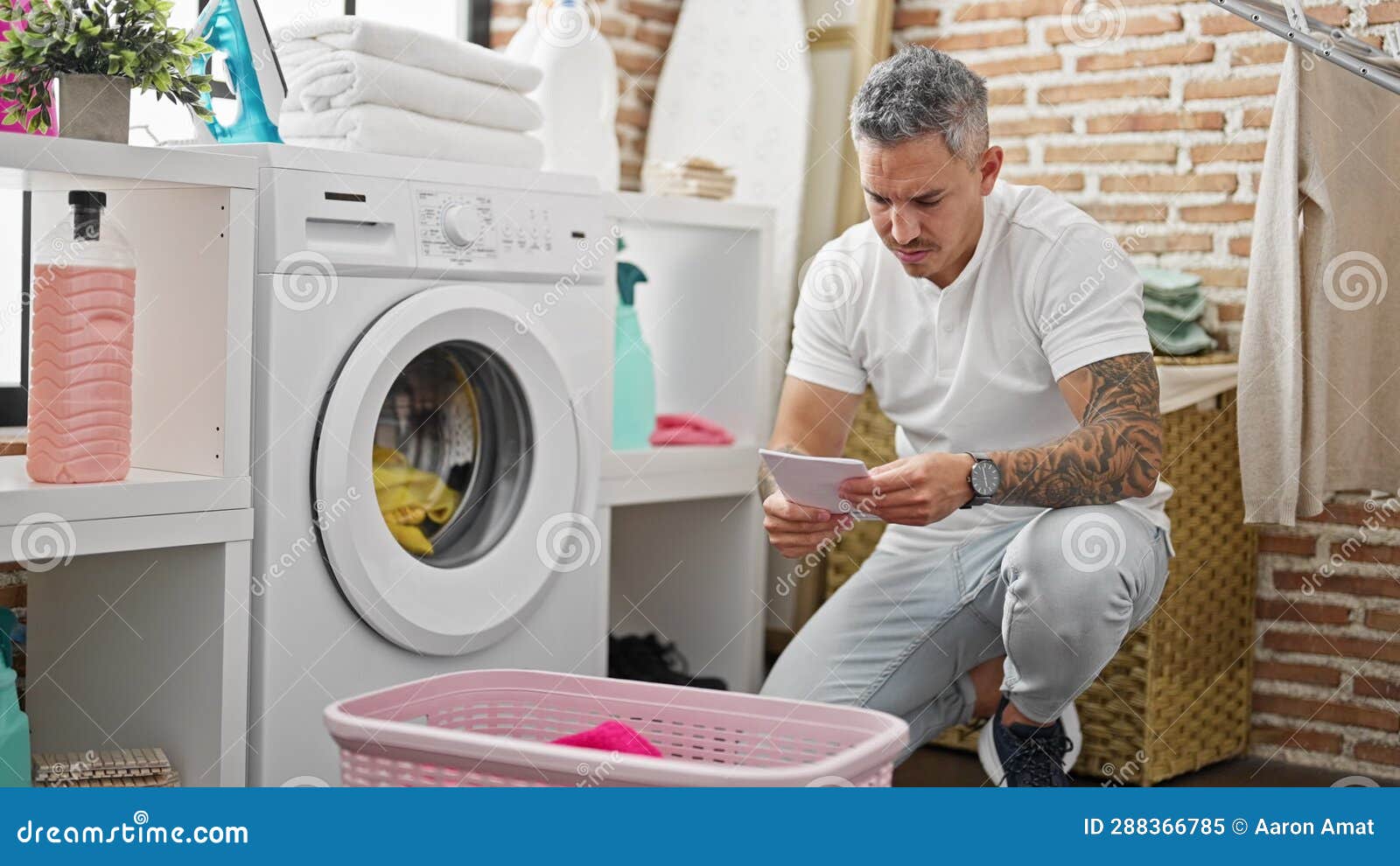 Young Hispanic Man Reading Instructions To Use Washing Machine at ...