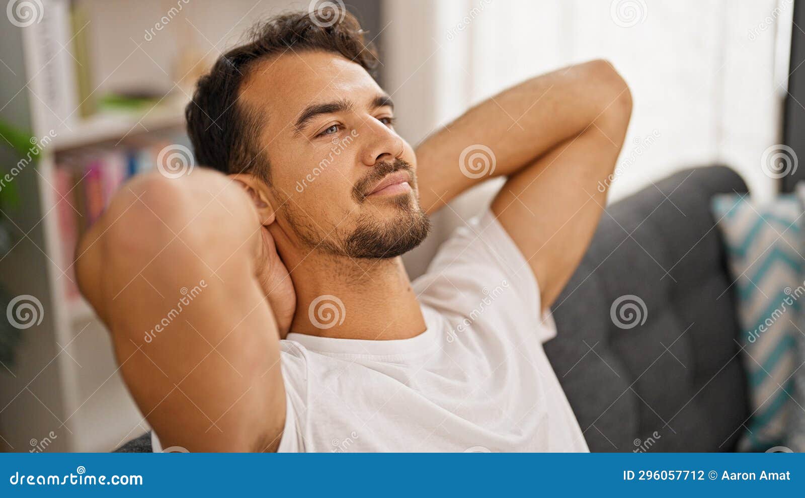 Young Hispanic Man Relaxed with Hands on Head Sitting on Sofa at Home ...