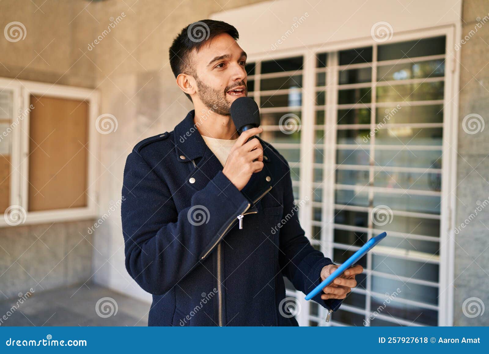 Young Hispanic Man Reporter Working Using Microphone and Touchpad at ...