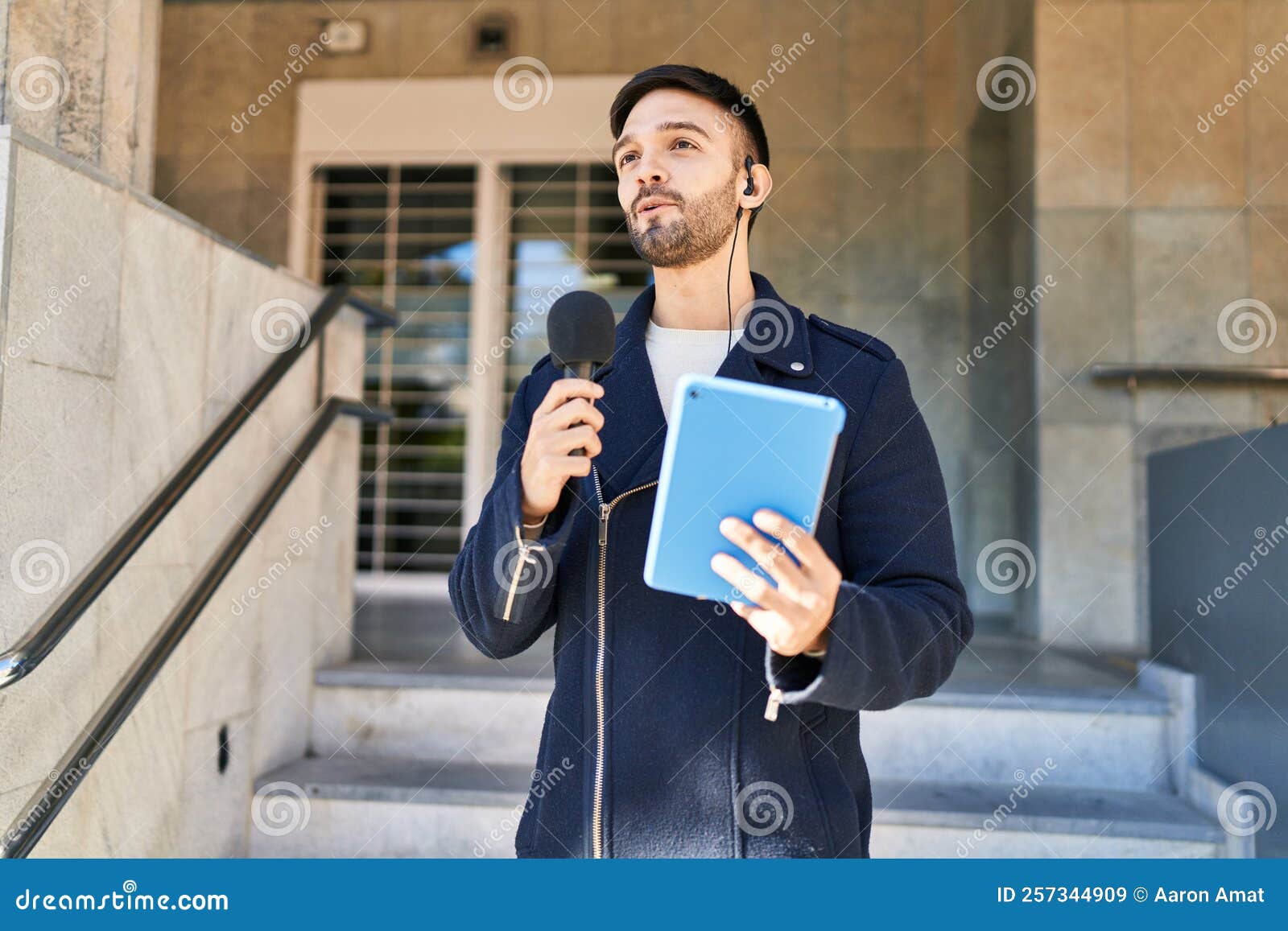 Young Hispanic Man Reporter Working Using Microphone and Touchpad at ...