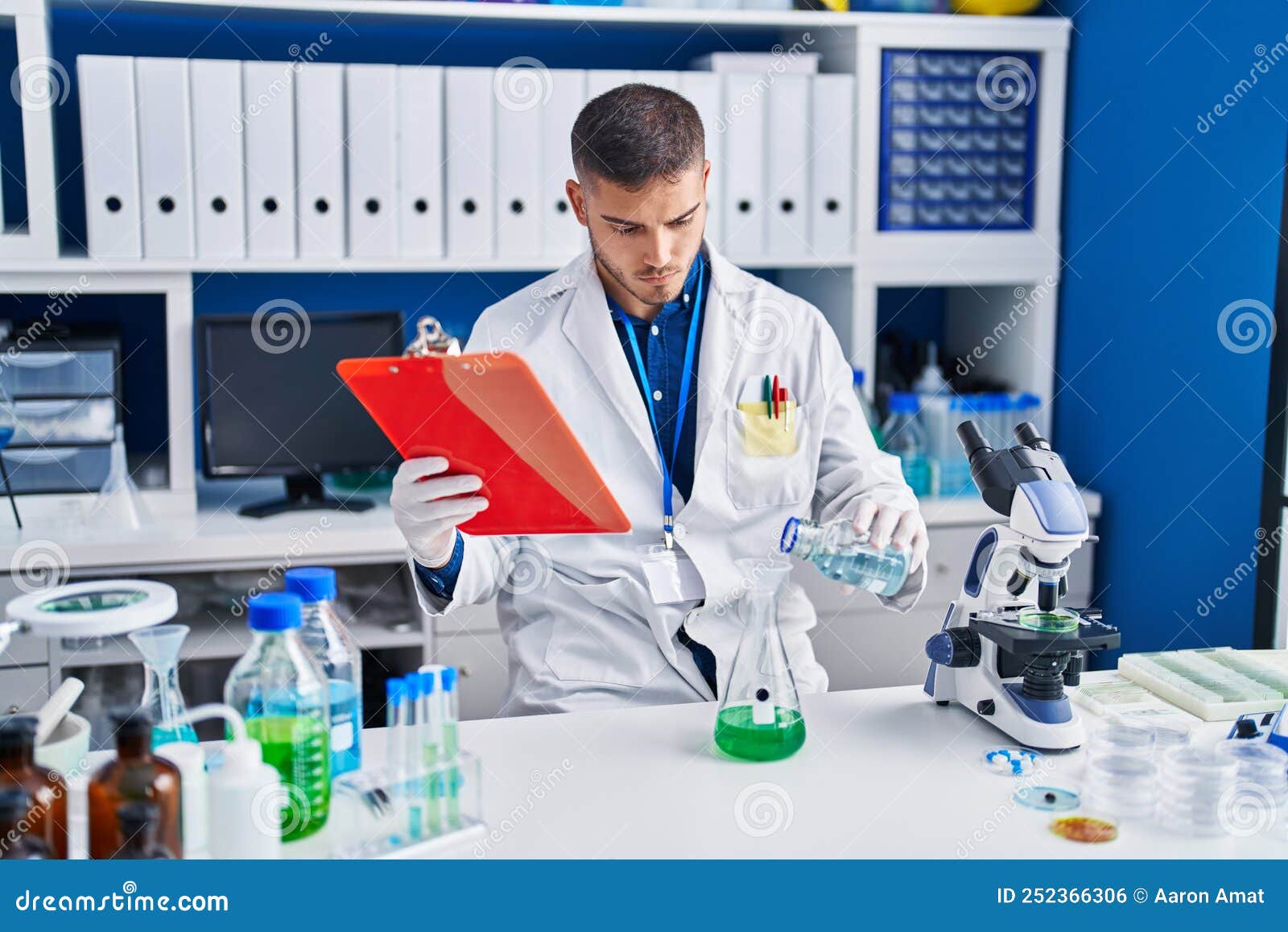 Young Hispanic Man Scientist Measuring Liquid at Laboratory Stock Photo ...