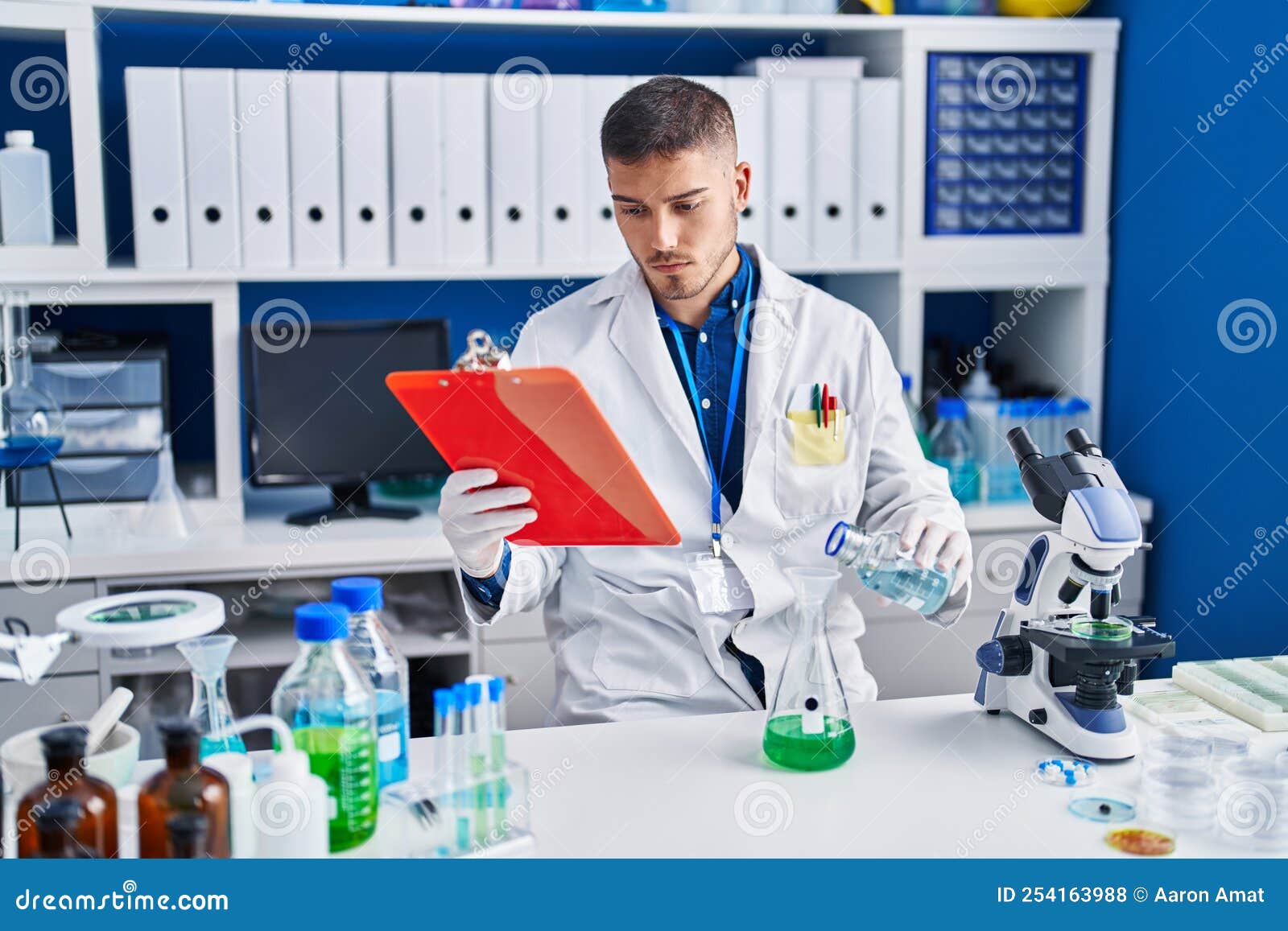 Young Hispanic Man Scientist Measuring Liquid at Laboratory Stock Photo ...