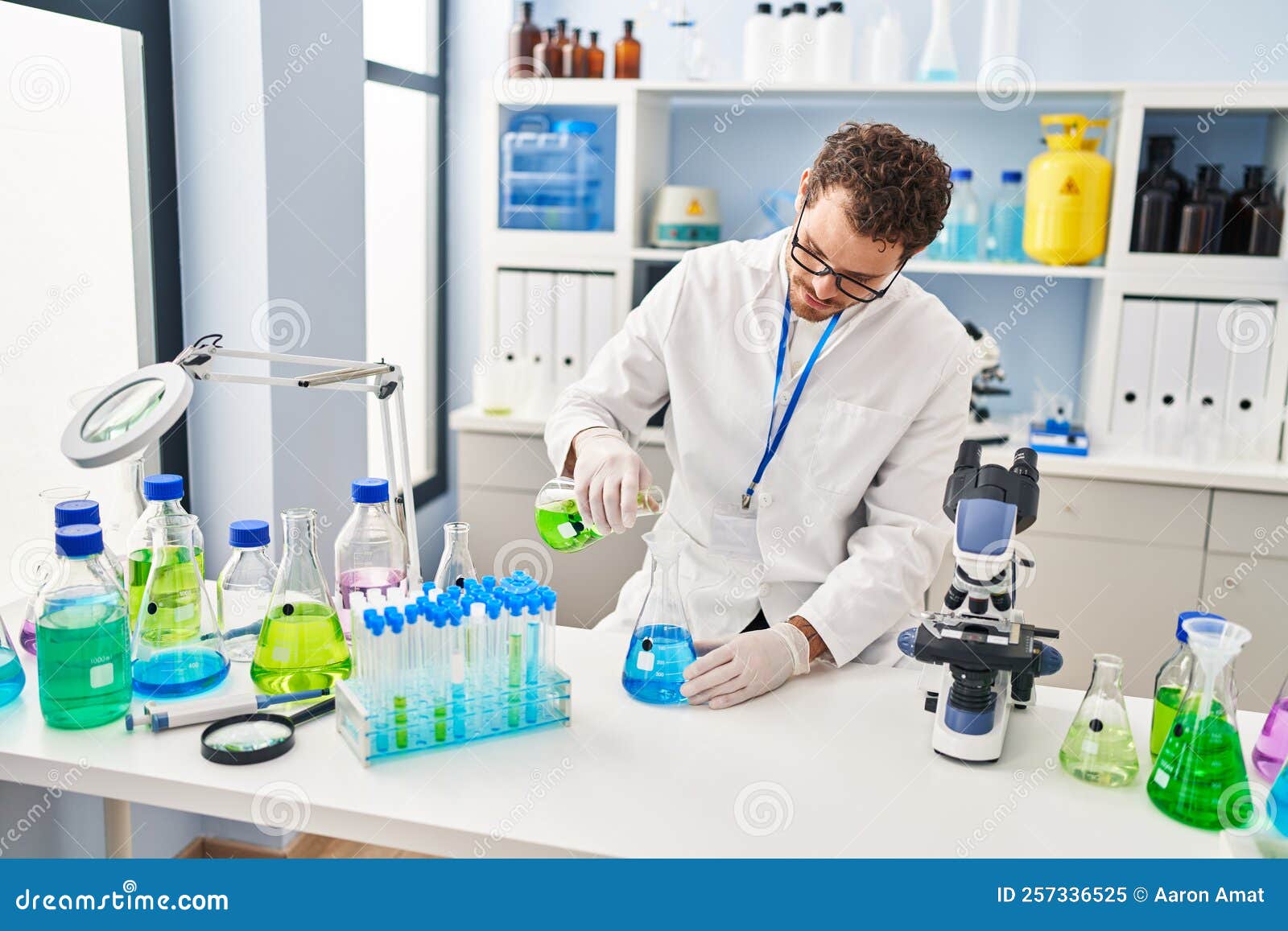 Young Hispanic Man Scientist Measuring Liquid at Laboratory Stock Image ...