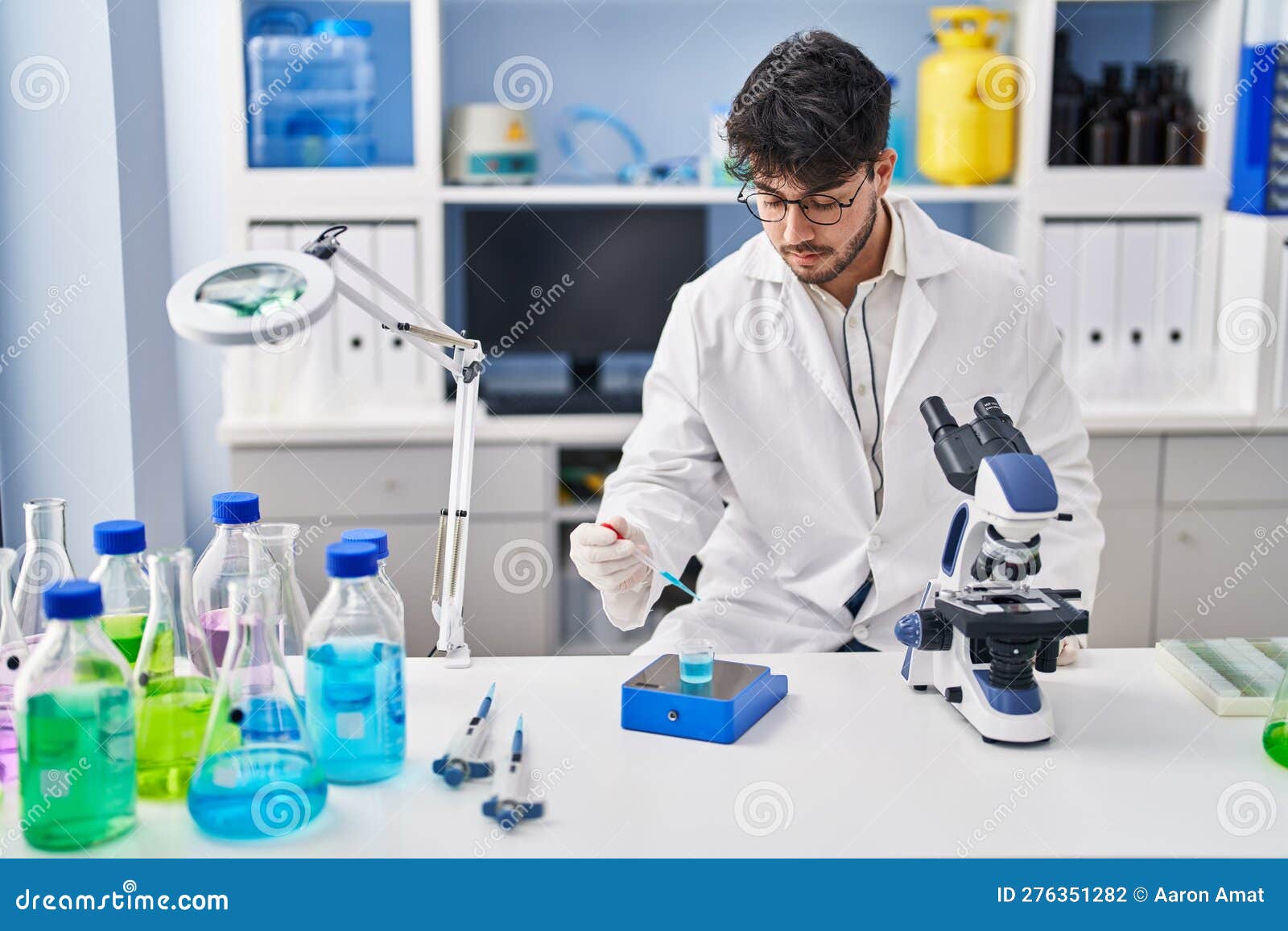 Young Hispanic Man Scientist Measuring Liquid at Laboratory Stock Photo ...