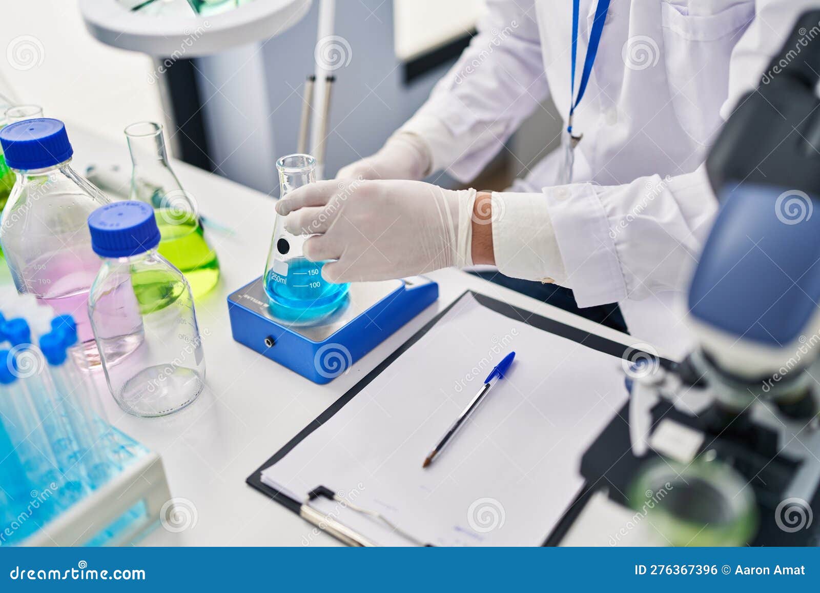 Young Hispanic Man Scientist Measuring Liquid Writing Report at ...