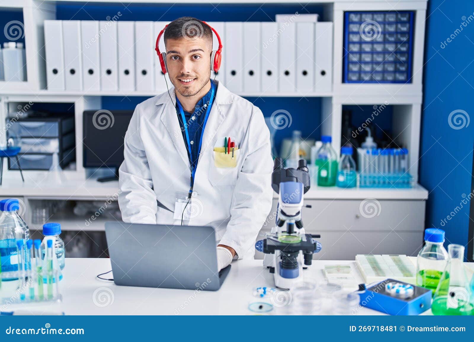 Young Hispanic Man Scientist Using Laptop and Headphones at Laboratory ...