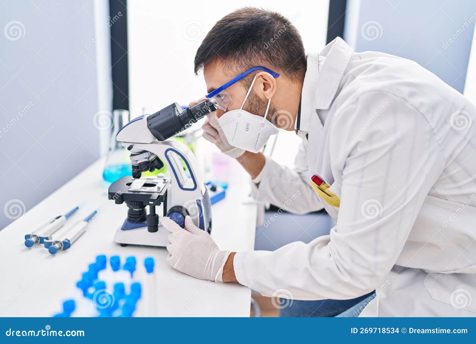 Young Hispanic Man Scientist Using Microscope Wearing Medical Mask at ...