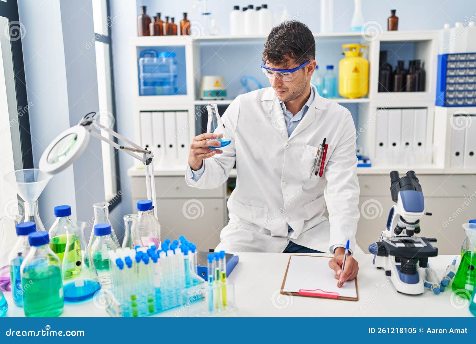 Young Hispanic Man Scientist Weighing Liquid Writing on Document at ...