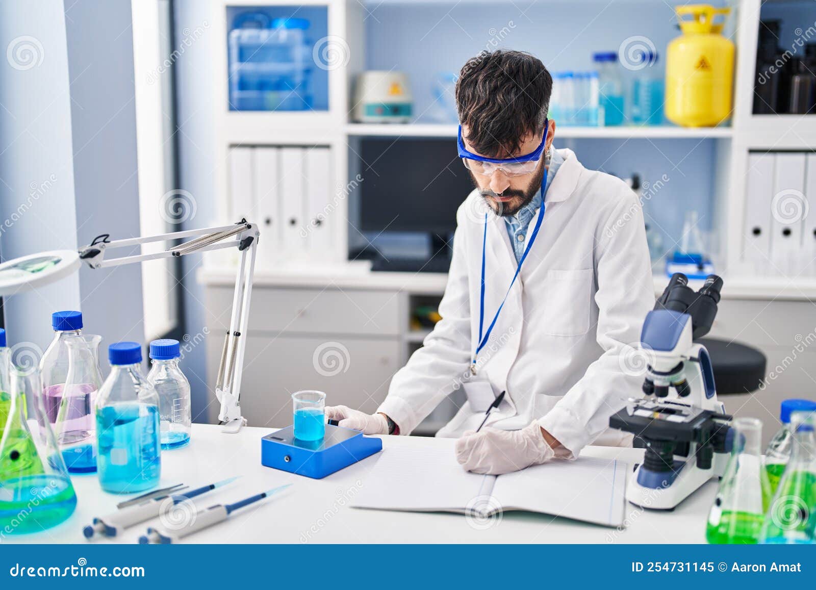 Young Hispanic Man Scientist Writing on Notebook Measuring Liquid at ...
