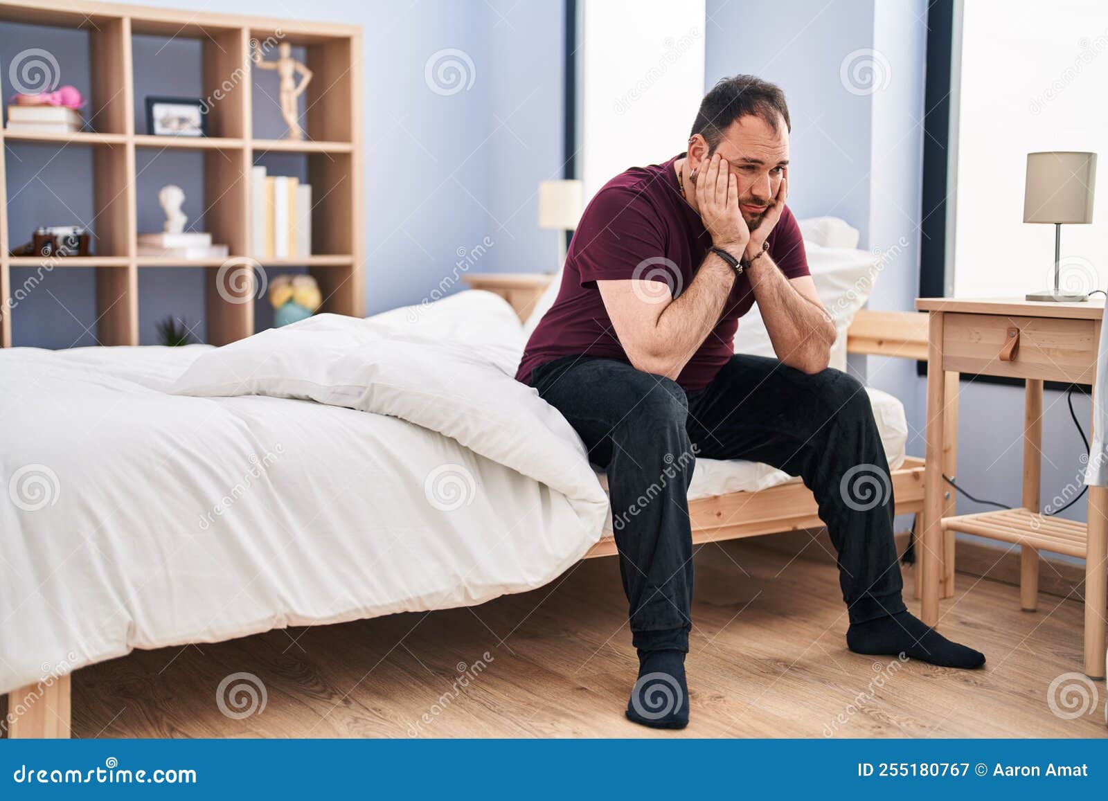 Young Hispanic Man Sitting on Bed with Sad Expression at Bedroom Stock ...