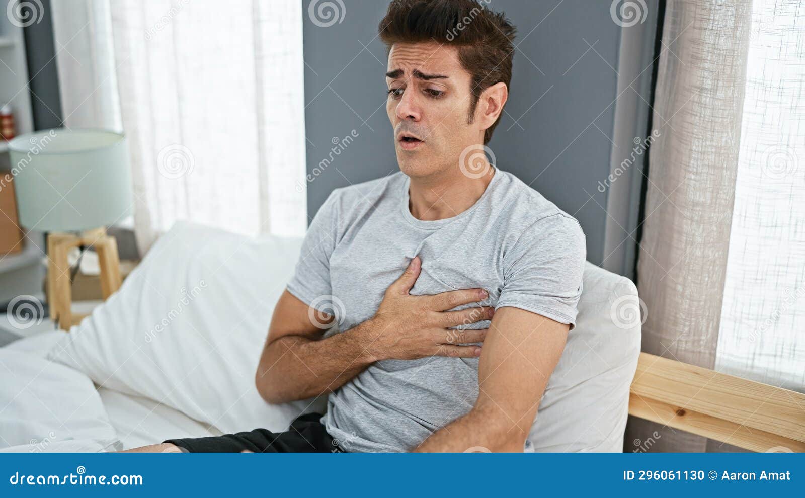 Young Hispanic Man Sitting on Bed Suffering Heart Attack at Bedroom ...