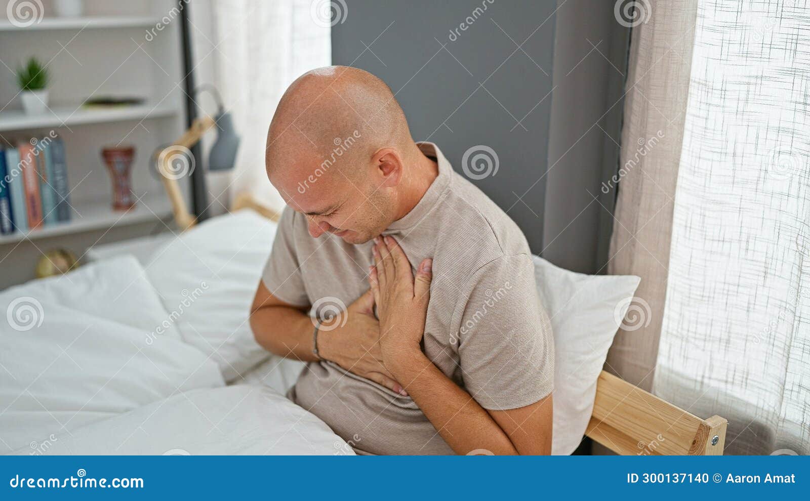 Young Hispanic Man Sitting on Bed Suffering Heart Attack at Bedroom ...