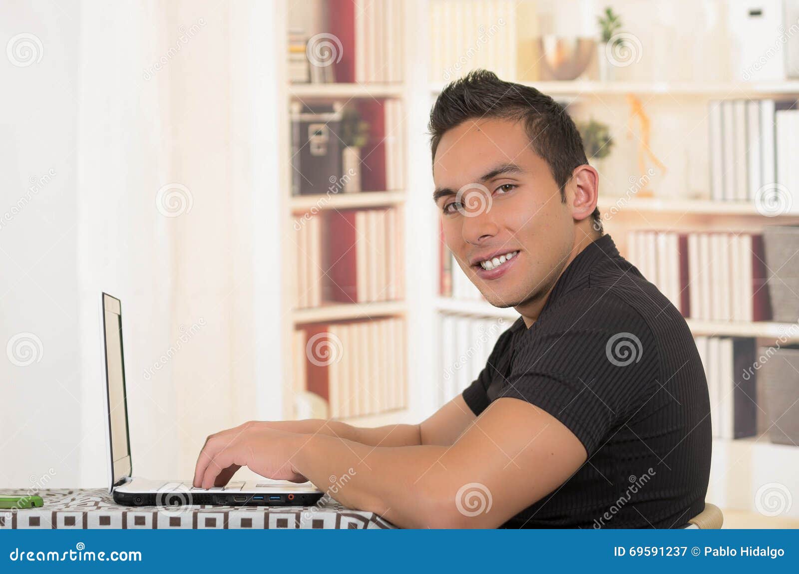 Young Hispanic Man Sitting at Desk Working on White Laptop, Profile ...