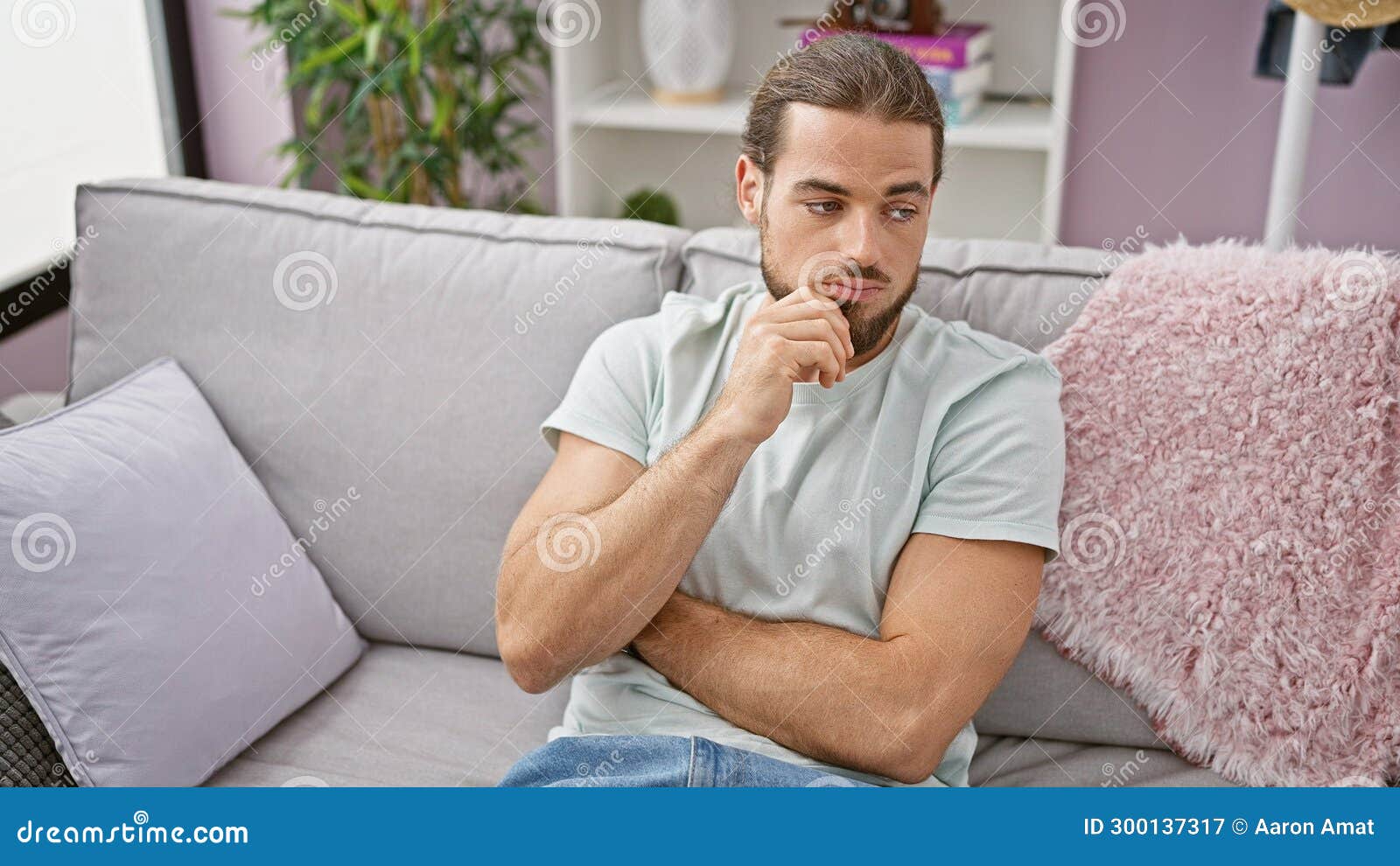 Young Hispanic Man Sitting on Sofa Thinking at Home Stock Image - Image ...
