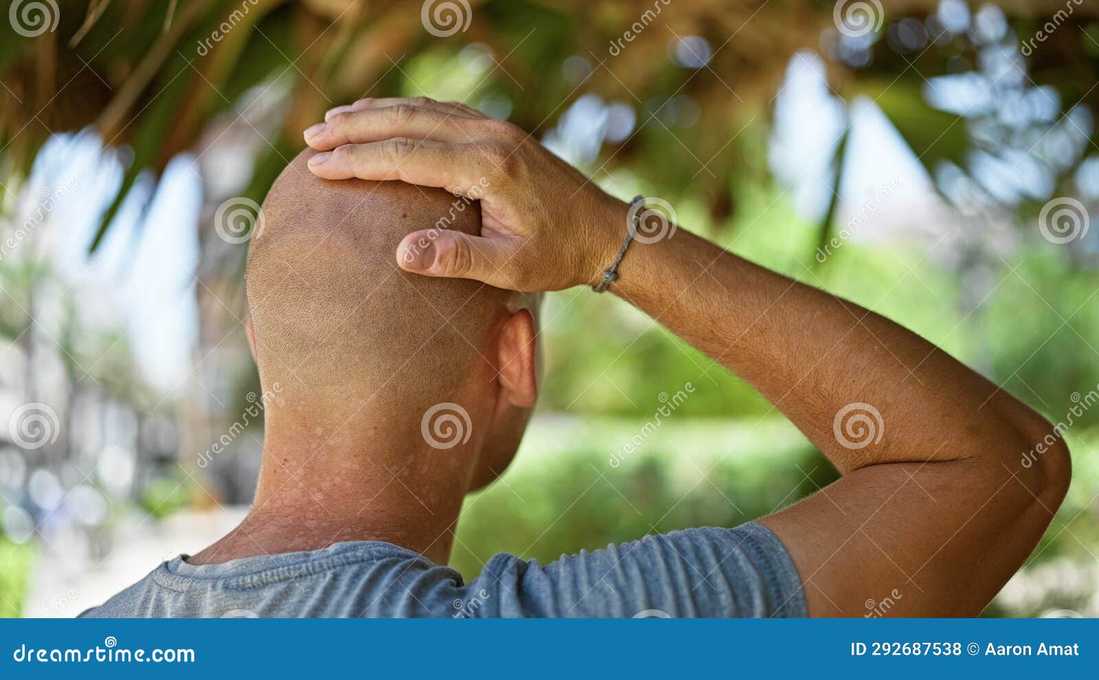 Young Hispanic Man Standing Backwards Touching Head at Park Stock ...