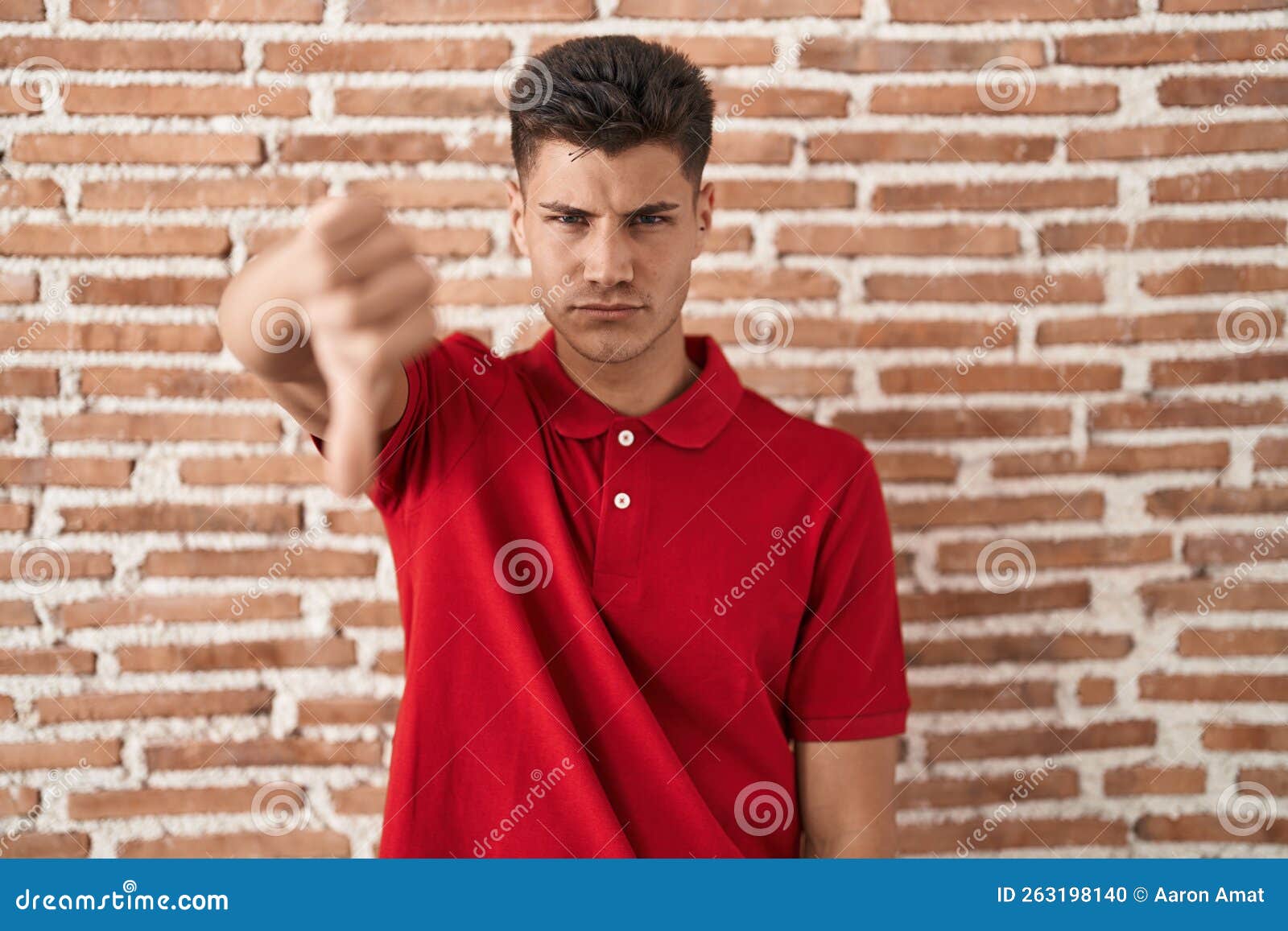 Young Hispanic Man Standing Over Bricks Wall Looking Unhappy And Angry