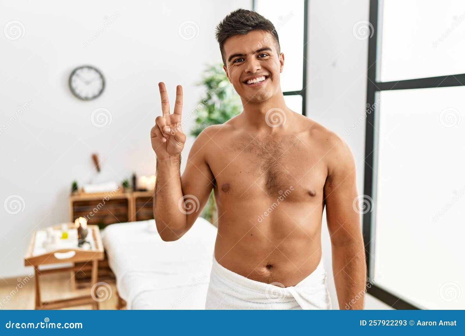 Young Hispanic Man Standing Shirtless At Spa Center Showing And