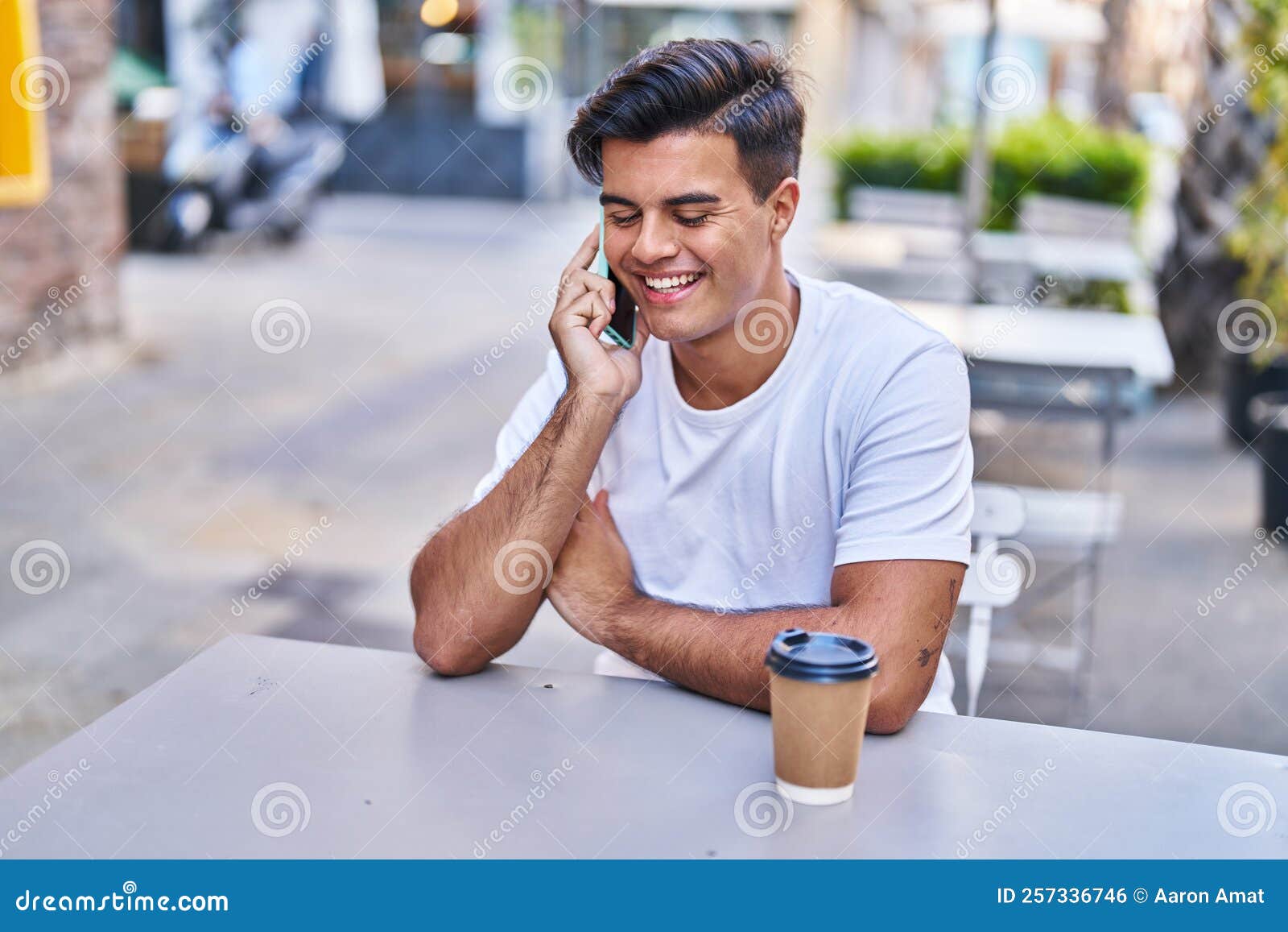 Young Hispanic Man Talking on Smartphone Drinking Coffee at Coffee Shop ...