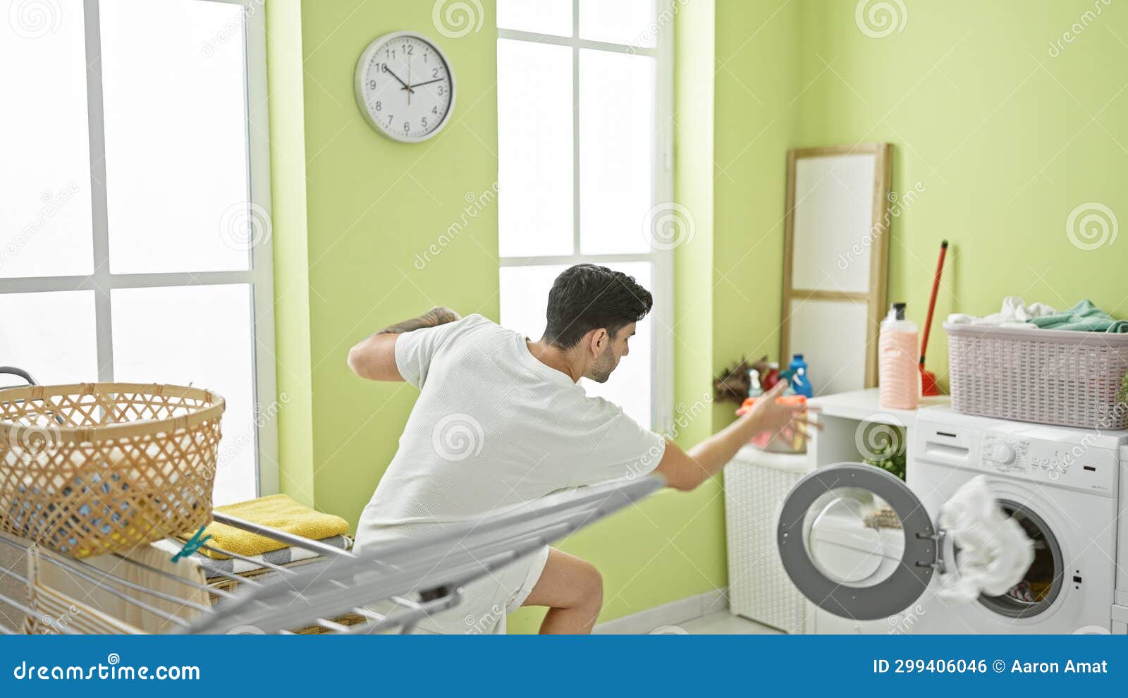 Young Hispanic Man Throwing Clothes on Washing Machine at Laundry Room ...