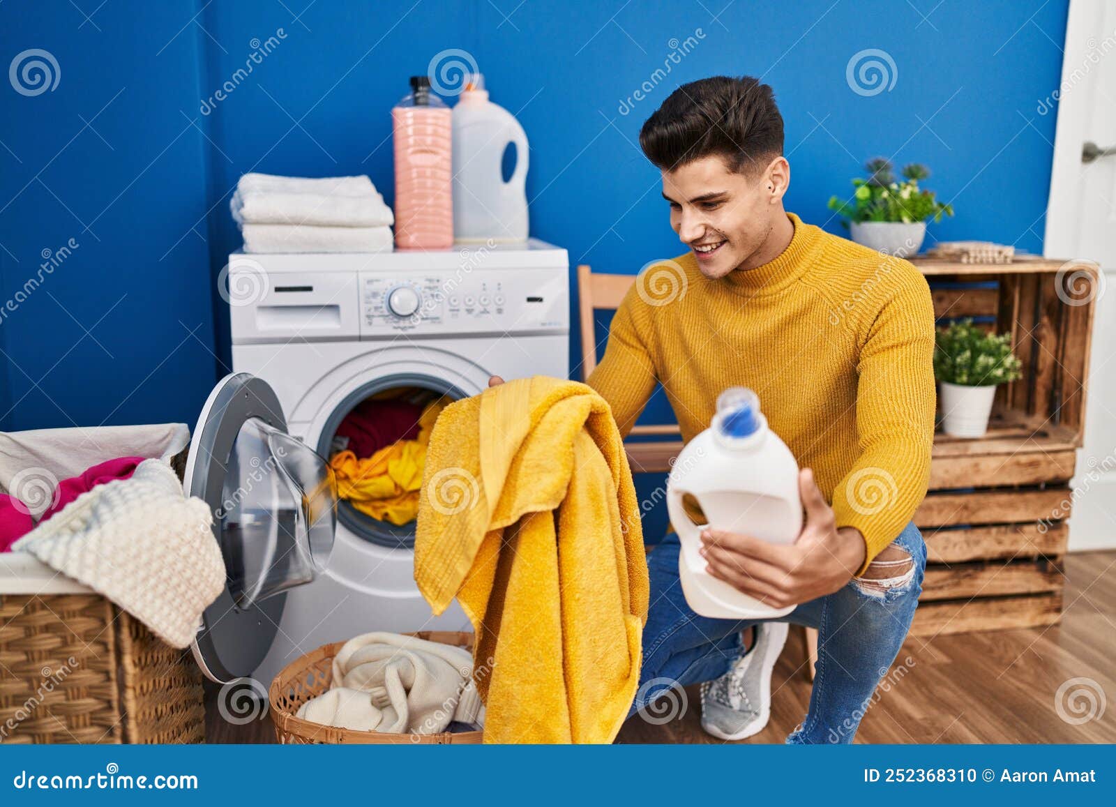 Young Hispanic Man Washing Clothes Holding Detergent Bottle at Laundry ...