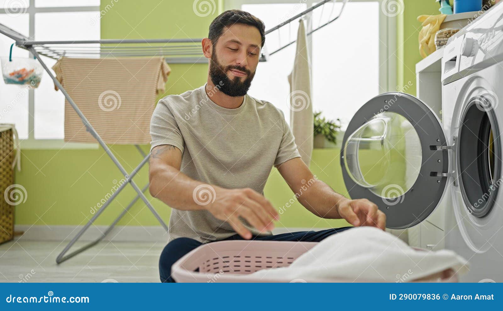Young Hispanic Man Washing Clothes Smiling at Laundry Room Stock Photo ...