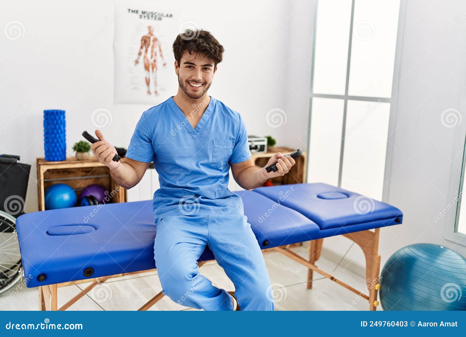 Young Hispanic Man Wearing Physio Therapist Uniform Using Grip Hand at ...