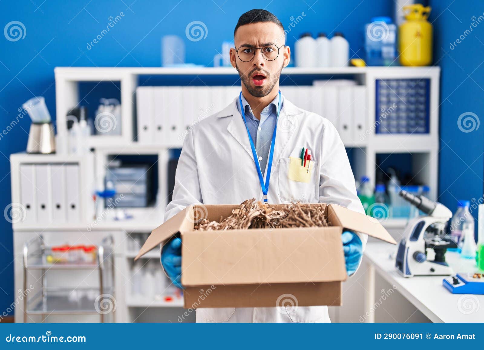 Young Hispanic Man Working at Scientist Laboratory Holding Cardboard ...