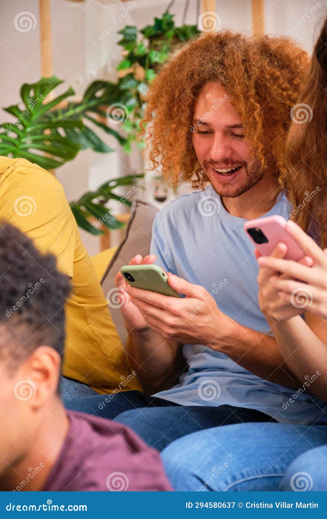 Young Hispanic Man Using His Smartphone Sitting with Friends. Stock ...