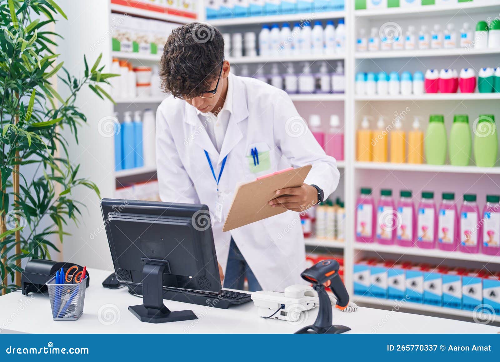 Young Hispanic Teenager Pharmacist Using Computer Reading Document at ...