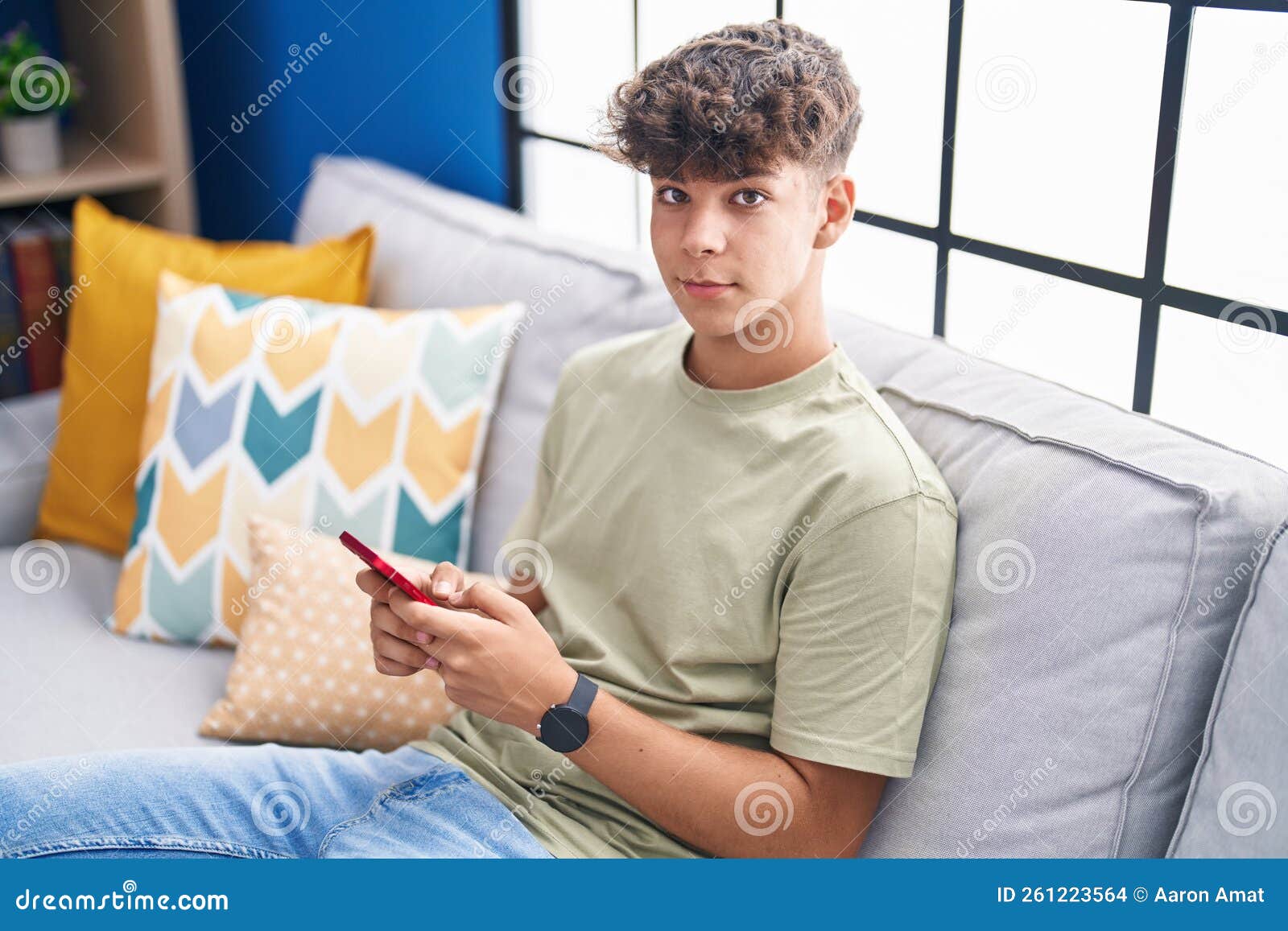 Young Hispanic Teenager Using Smartphone Sitting on Sofa at Home Stock ...