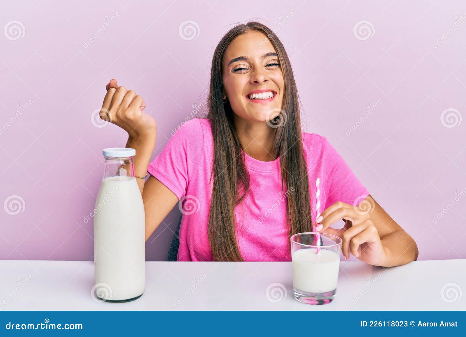 Young Hispanic Woman Drinking A Glass Of Fresh Milk Sitting On The