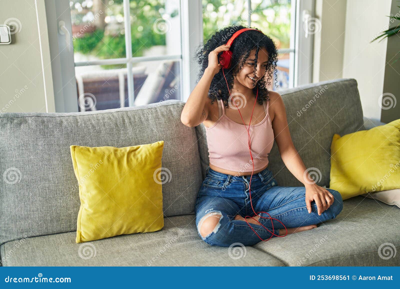 Young Hispanic Woman Listening To Music Sitting On Sofa At Home Stock