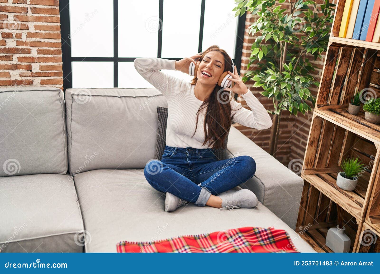 Young Hispanic Woman Listening To Music Sitting On Sofa At Home Stock