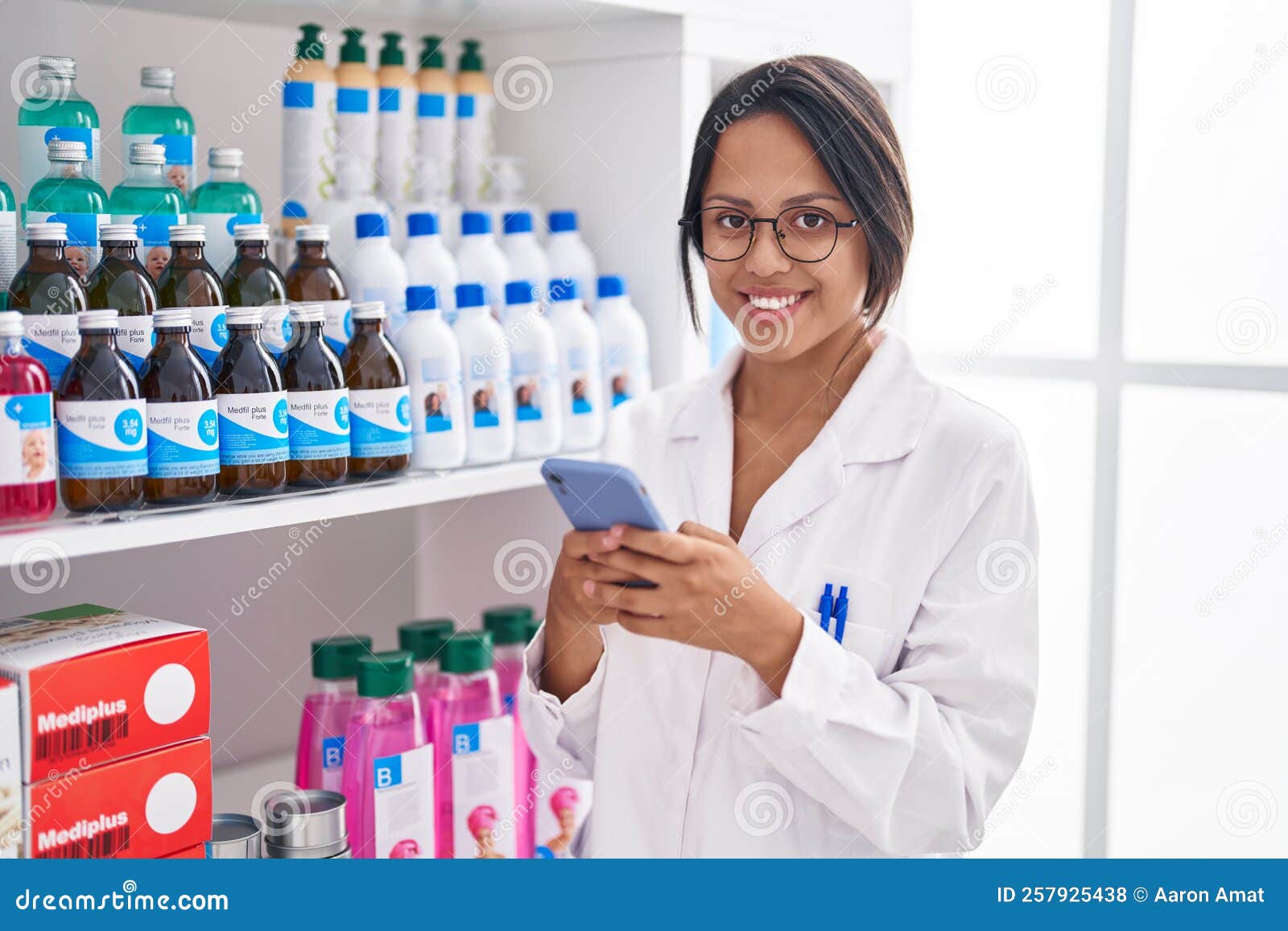 Young Hispanic Woman Pharmacist Using Smartphone Working at Pharmacy ...