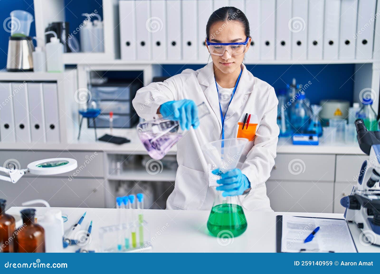 Young Hispanic Woman Scientist Measuring Liquid at Laboratory Stock ...