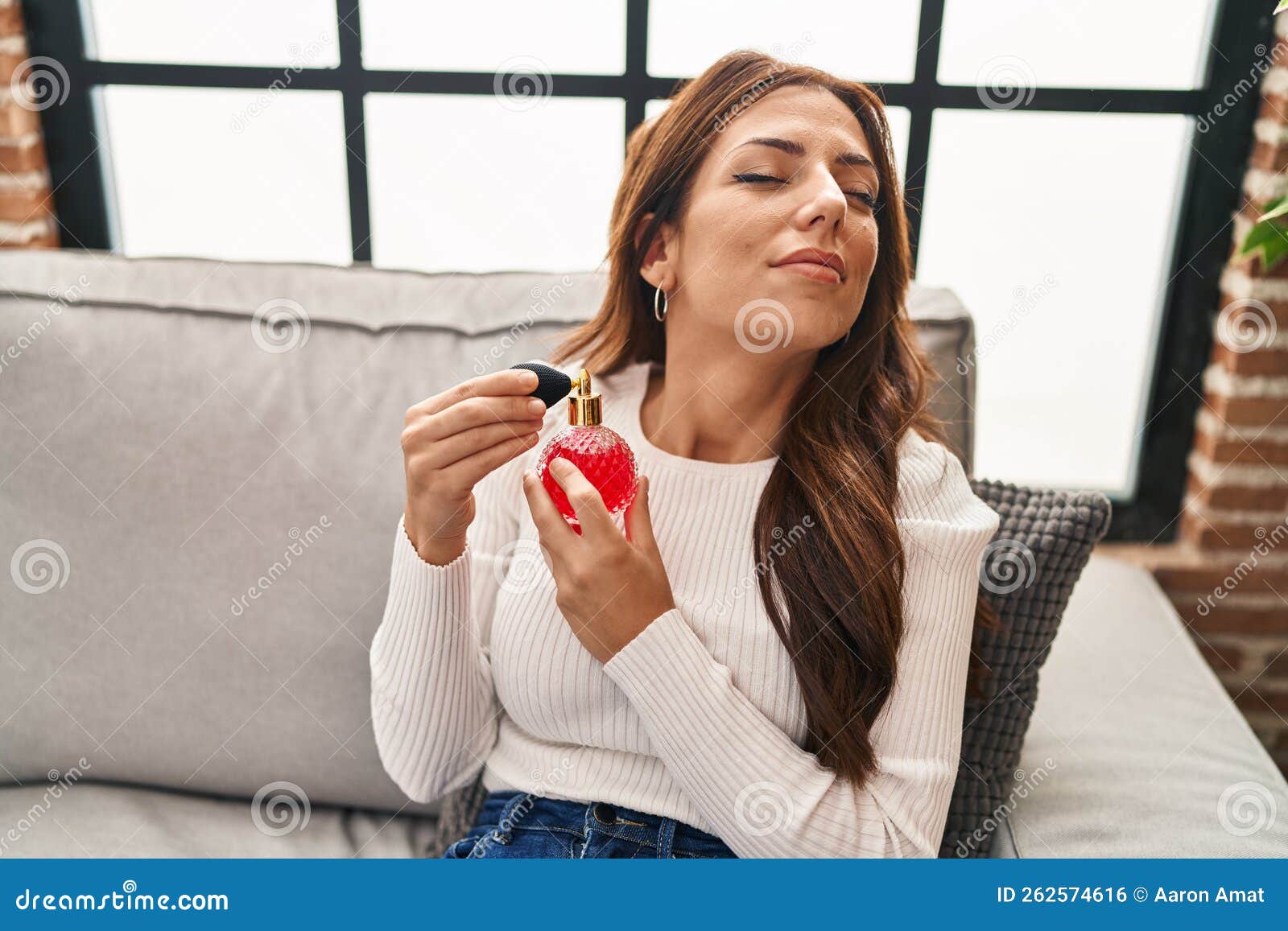 Young Hispanic Woman Smiling Confident Using Perfume at Home Stock ...