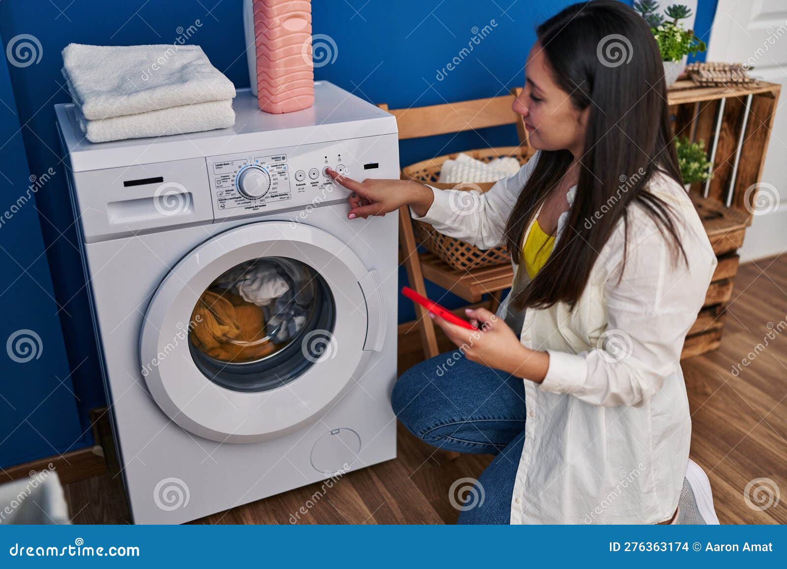 Young Hispanic Woman Turning on Washing Machine Using Smartphone at ...