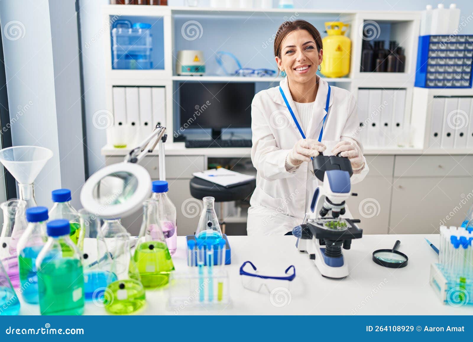 Young Hispanic Woman Wearing Scientist Uniform Using Microscope at ...