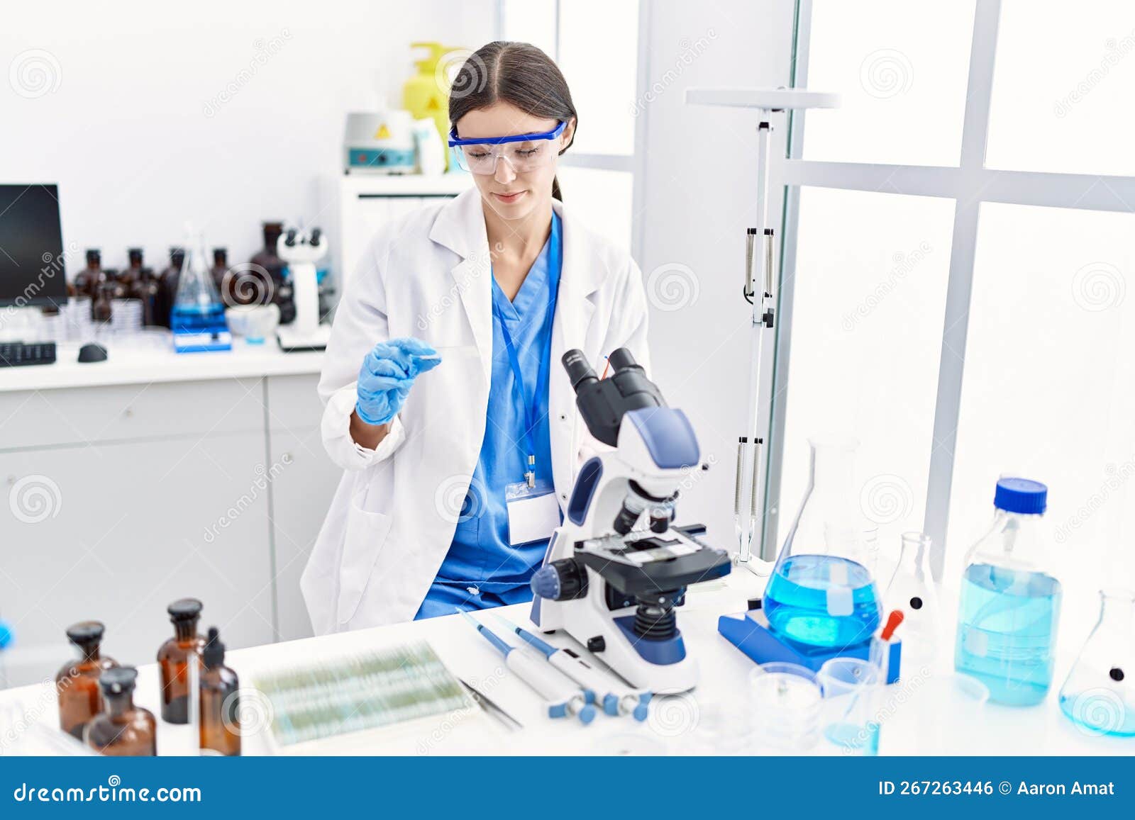 Young Hispanic Woman Wearing Scientist Uniform Using Microscope at ...