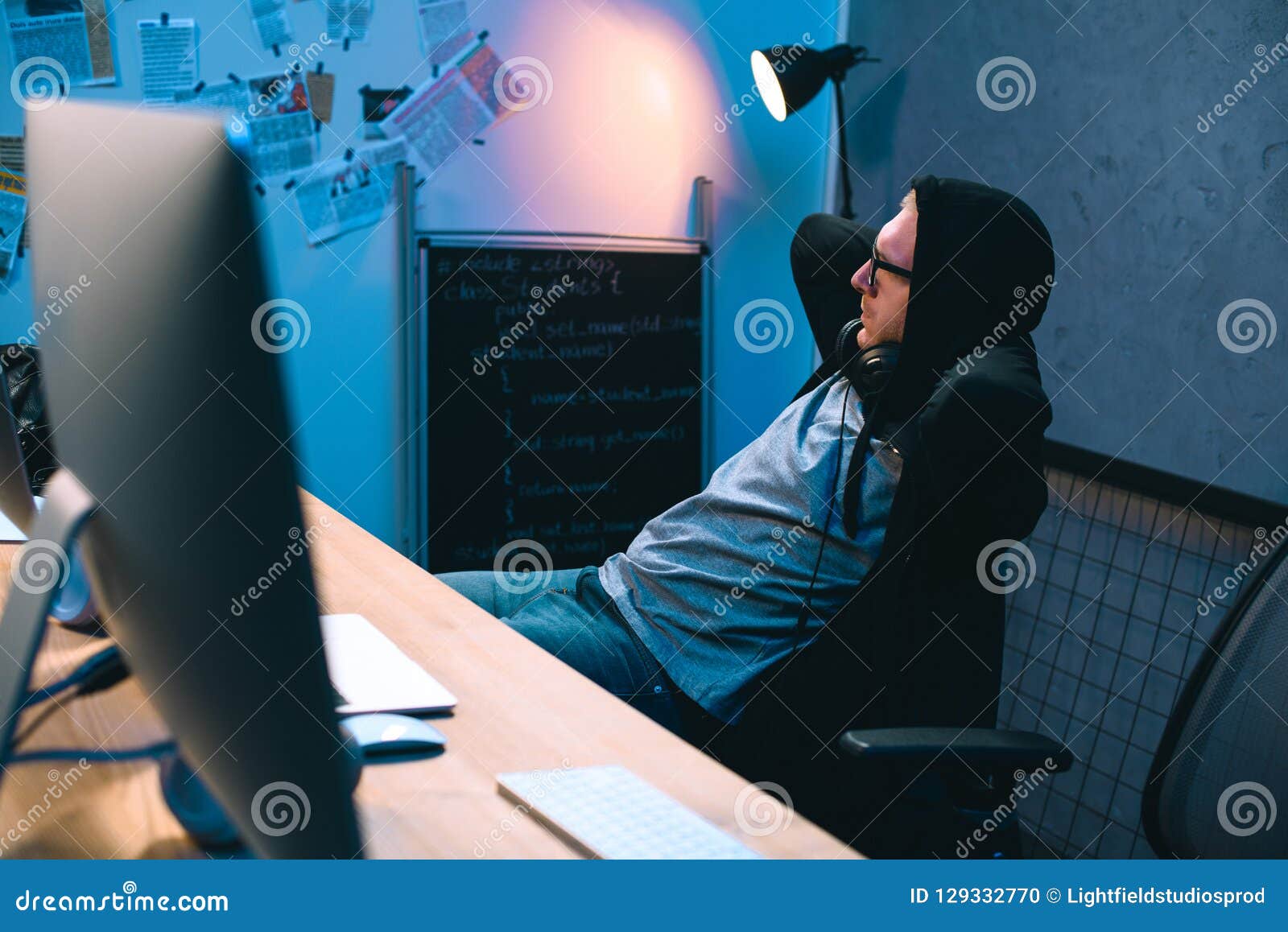 Young Hooded Hacker Relaxing on Chair in Front of Stock Photo - Image ...