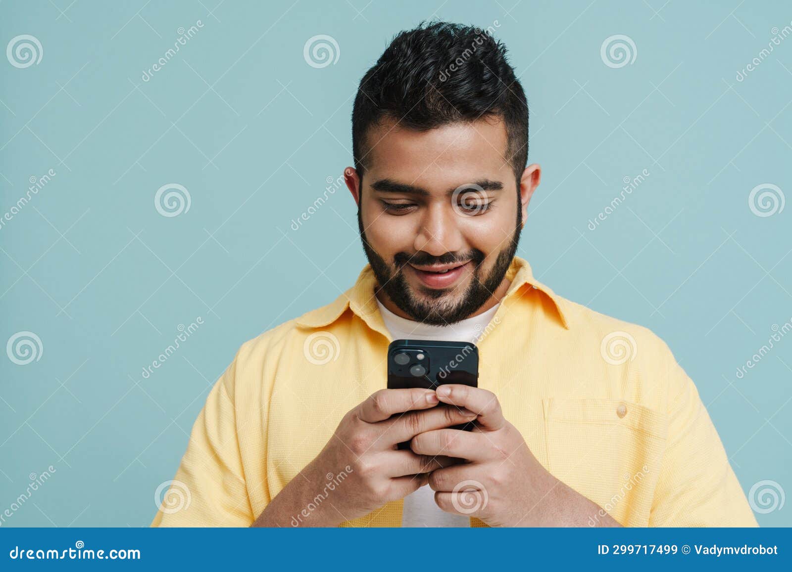 Young Indian Guy Using Mobile Phone Isolated Over Blue Wall Stock Image ...